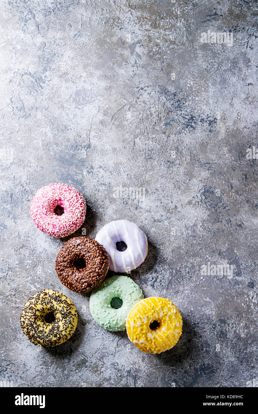 Variety of colorful glazed donuts over gray texture background. Top ...