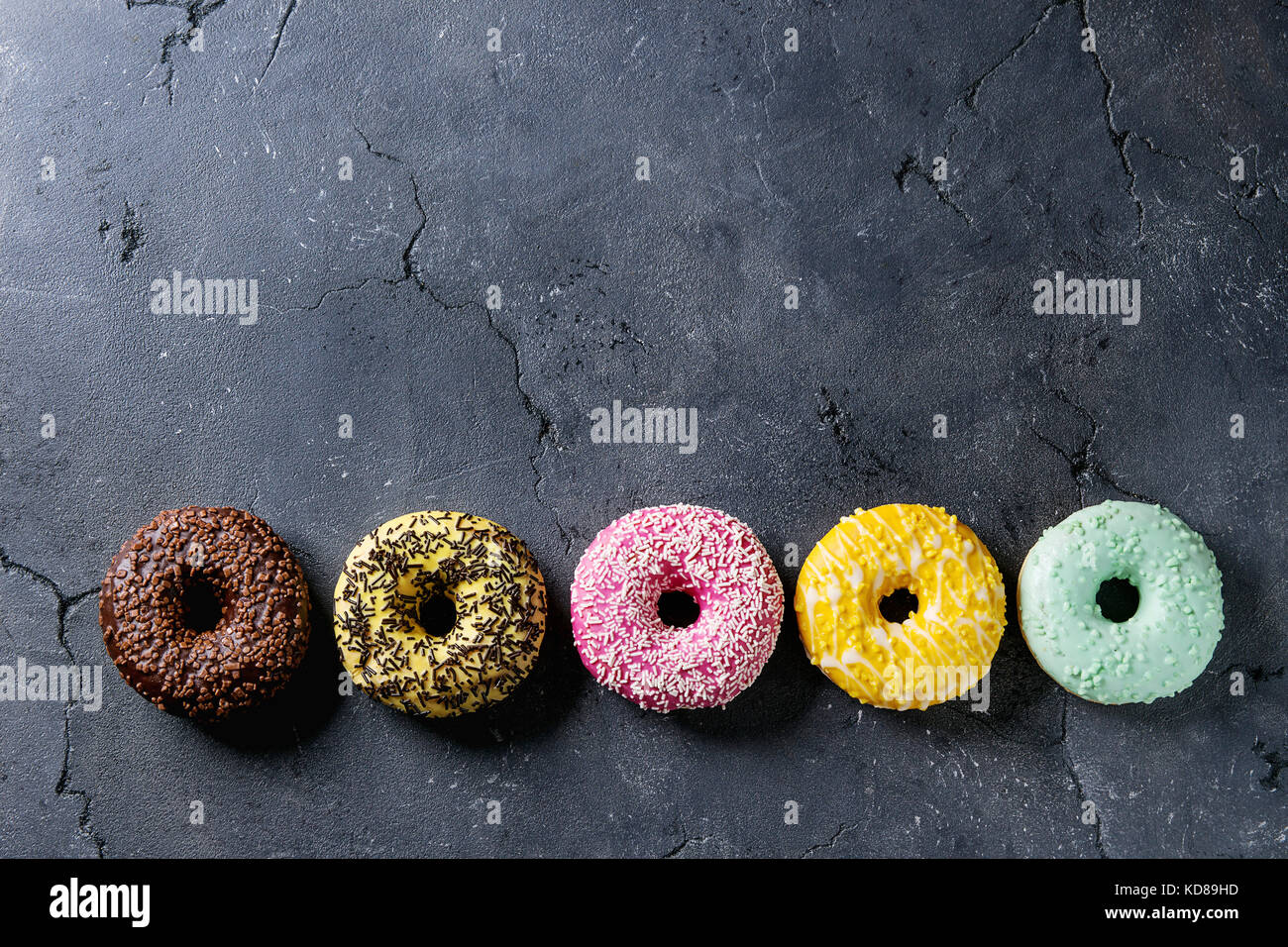 Variety of colorful glazed donuts over black texture background. Top ...