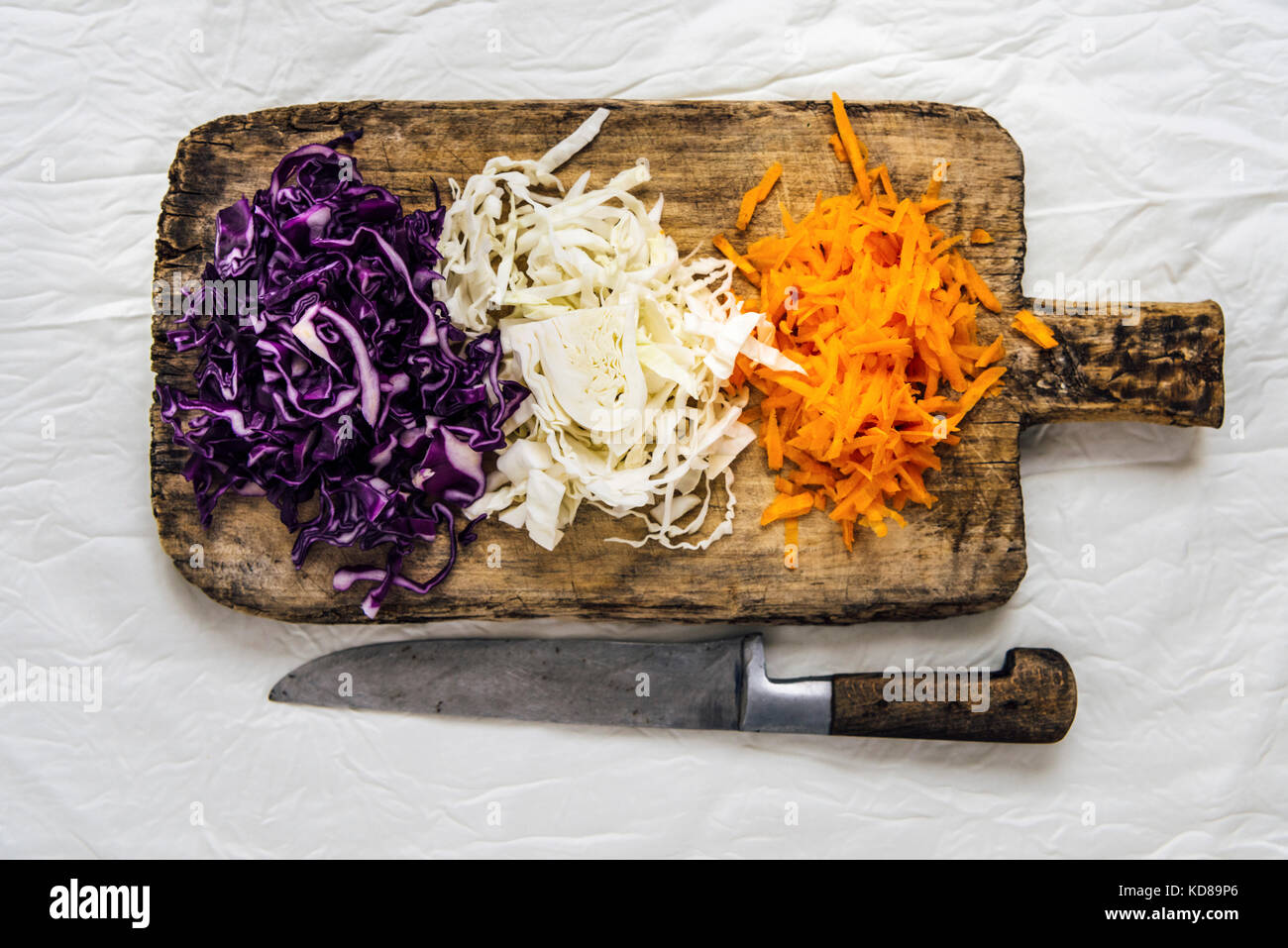 Shredded white cabbage, purple cabbage and carrot ready on a wooden ...