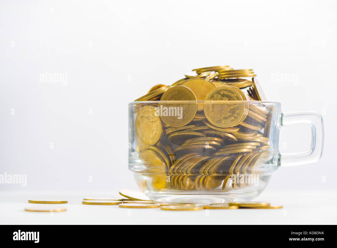 Golden coins in a glass of coffee, on the white background, saving ...