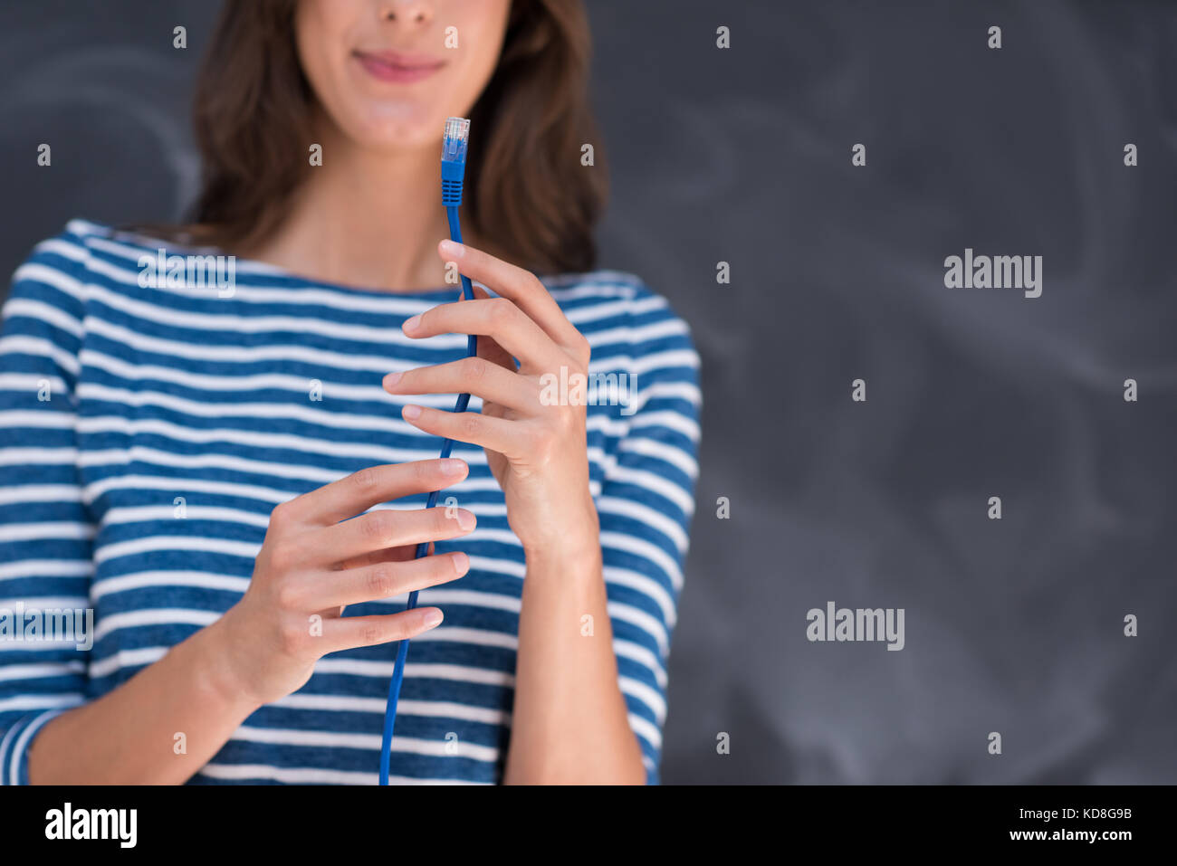 portrait of a young woman holding a internet cable in front of chalk ...