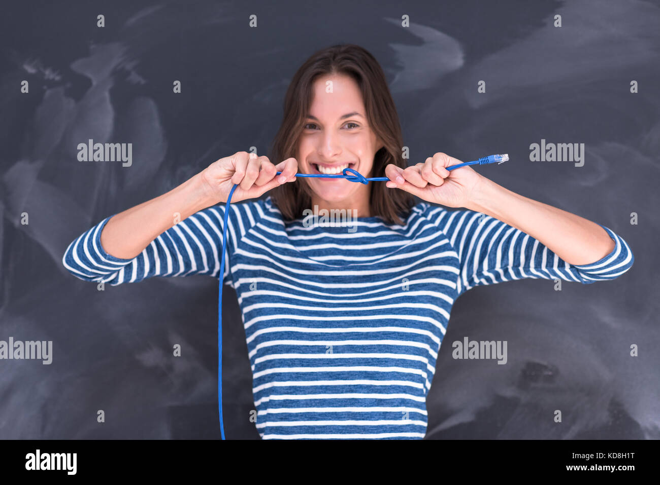 portrait of a young woman holding a internet cable in front of chalk ...