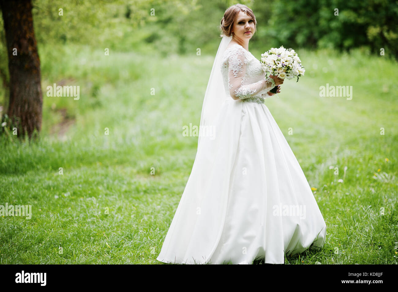 Portrait of a beautiful young bride posing with a bouquet outdoor on ...