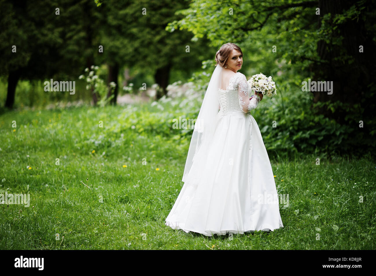 Portrait of a beautiful young bride posing with a bouquet outdoor on ...