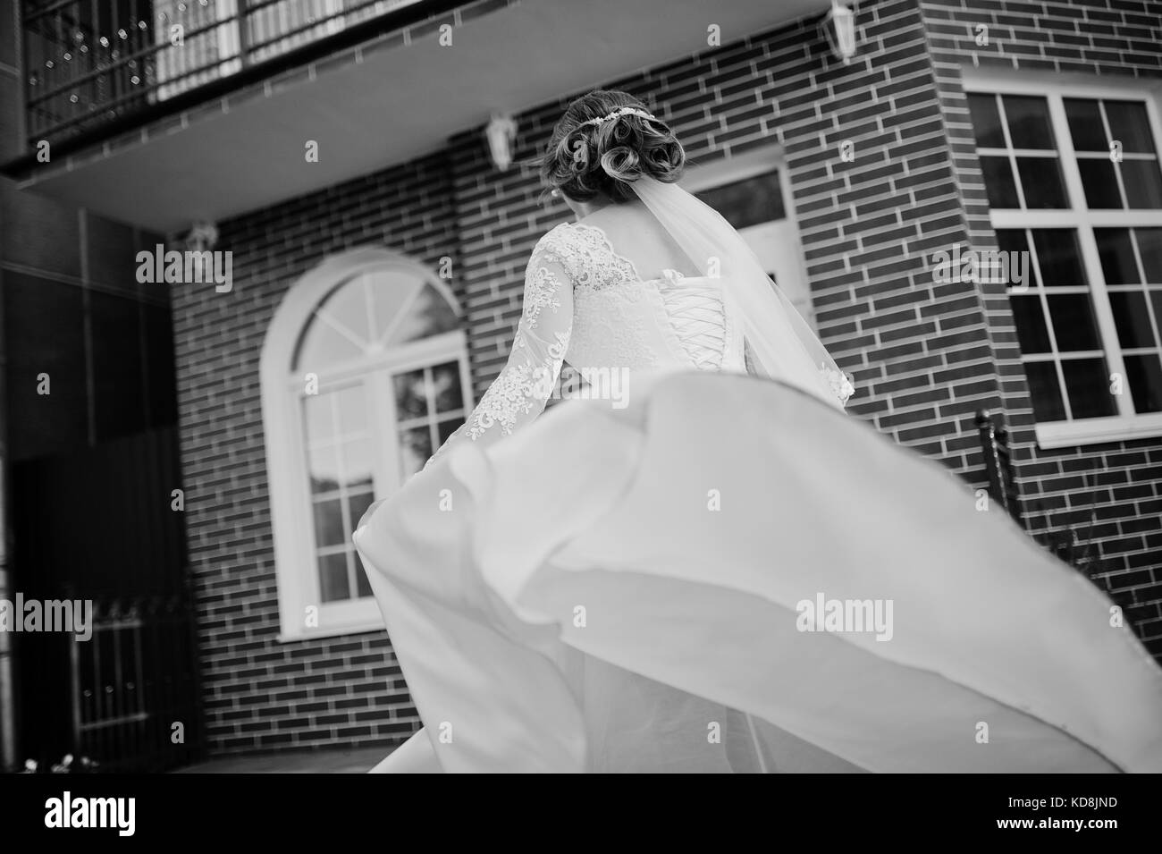 Portrait of an attractive bride spinning in front of a house with a ...