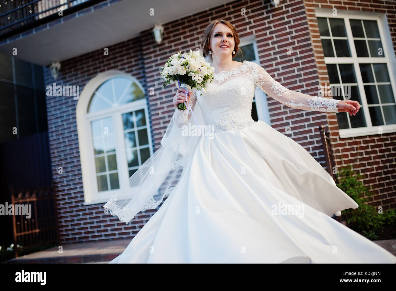 Portrait of an attractive bride spinning in front of a house with a ...