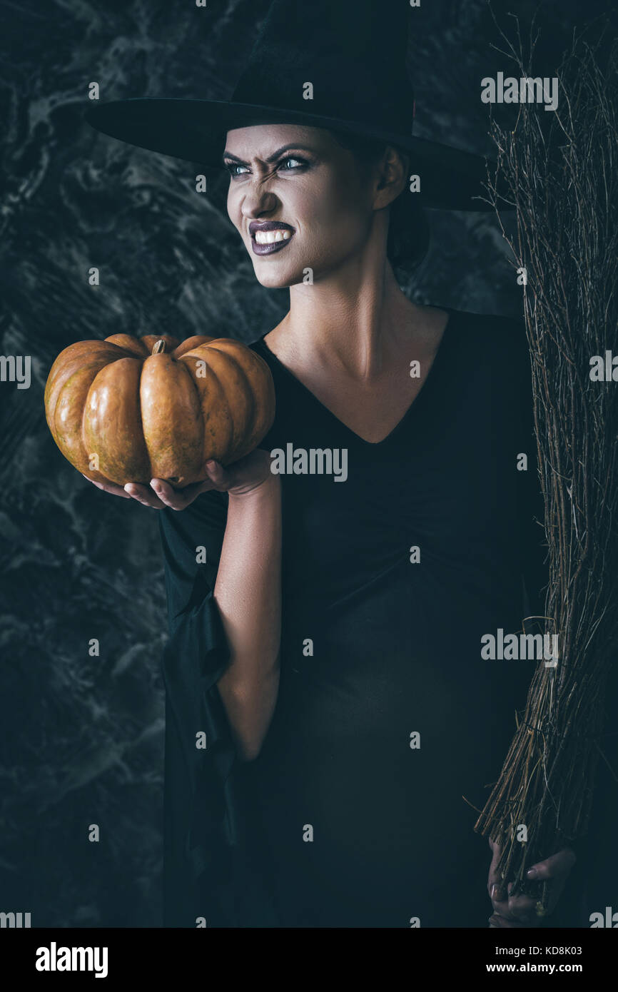Halloween Witch holding a pumpkin and a broom Stock Photo - Alamy