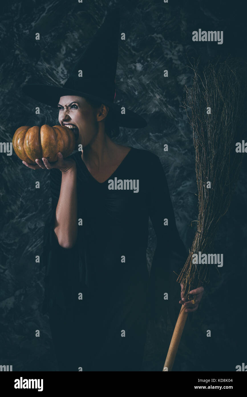 Halloween Witch holding a pumpkin and a broom Stock Photo - Alamy