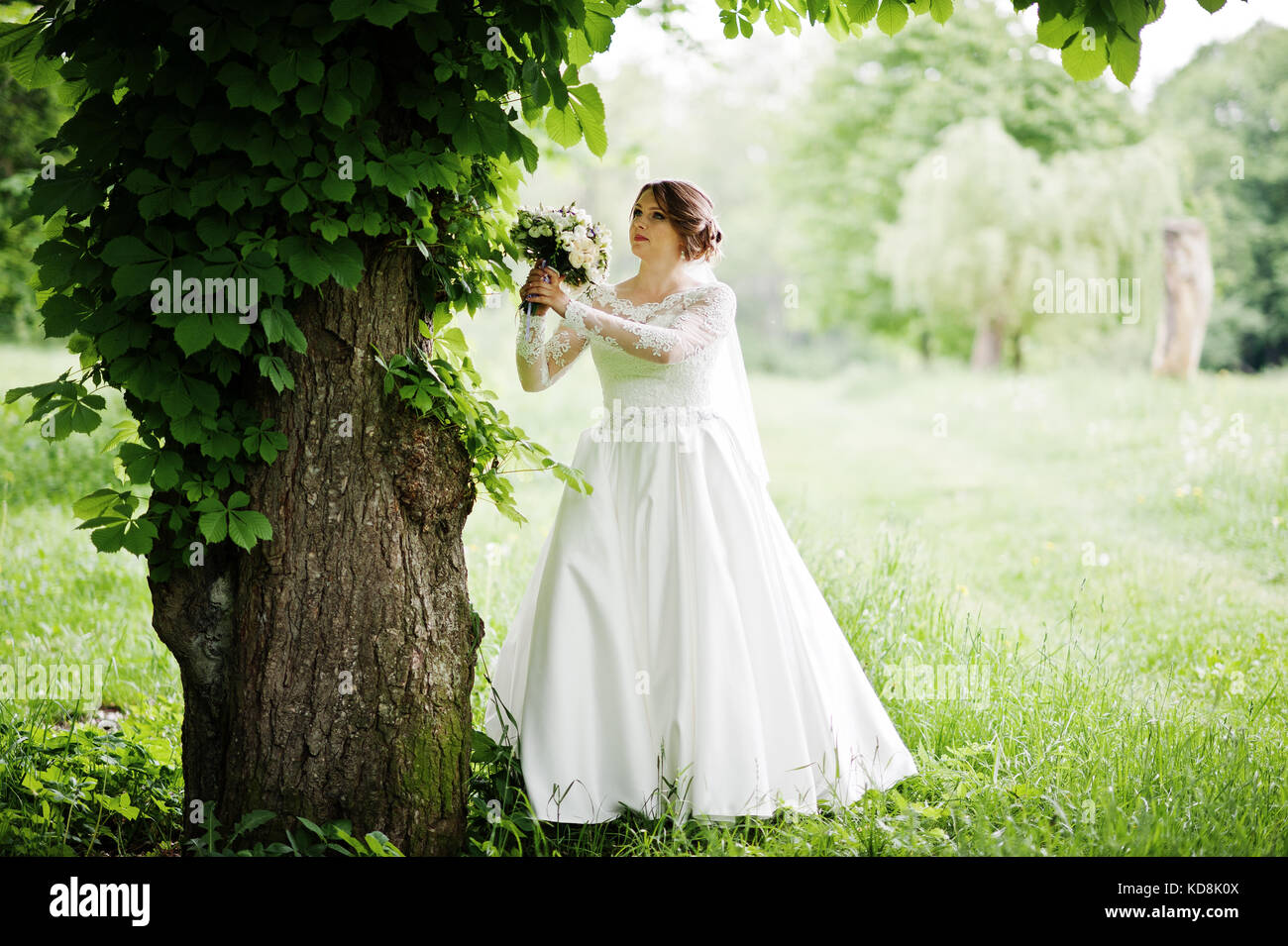Portrait of a beautiful young bride posing with a bouquet outdoor on ...