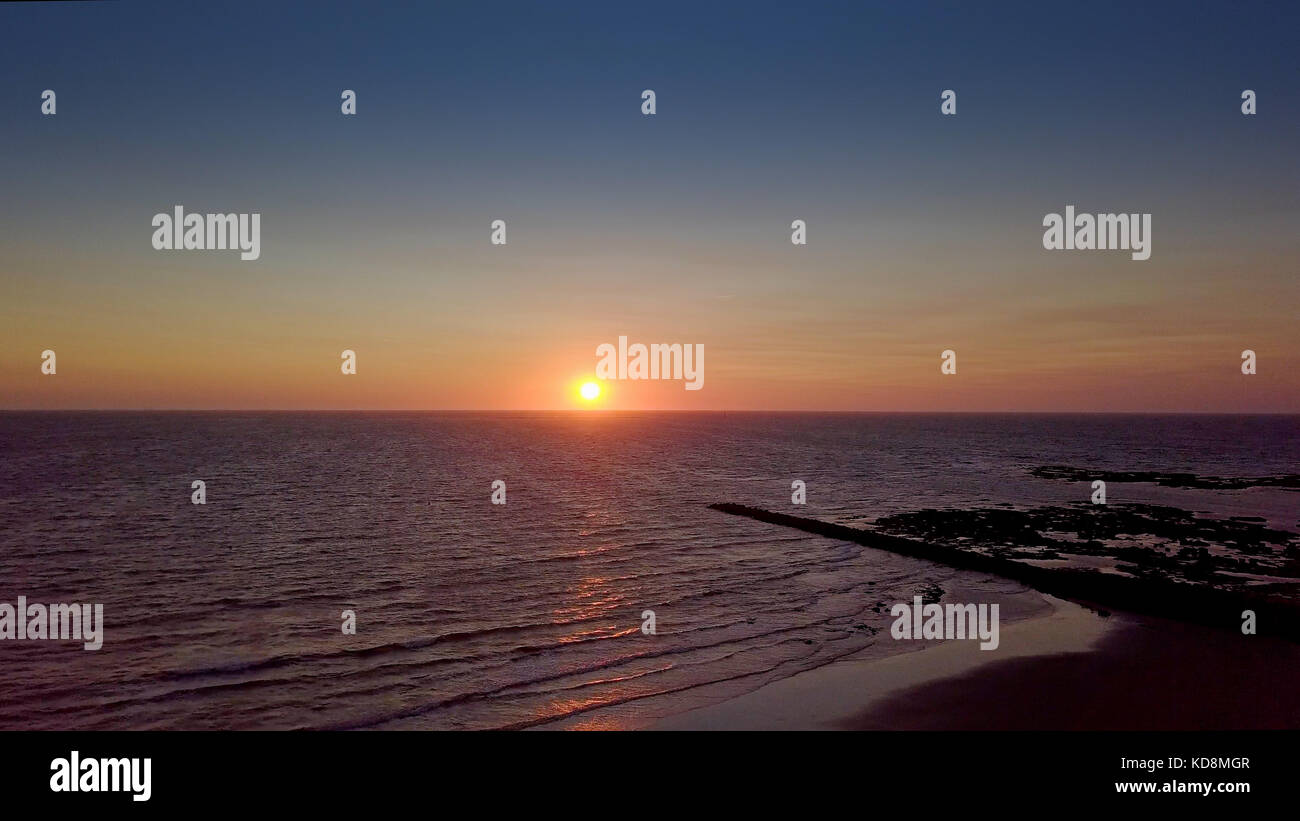 Sun rising above ocean water Stock Photo - Alamy