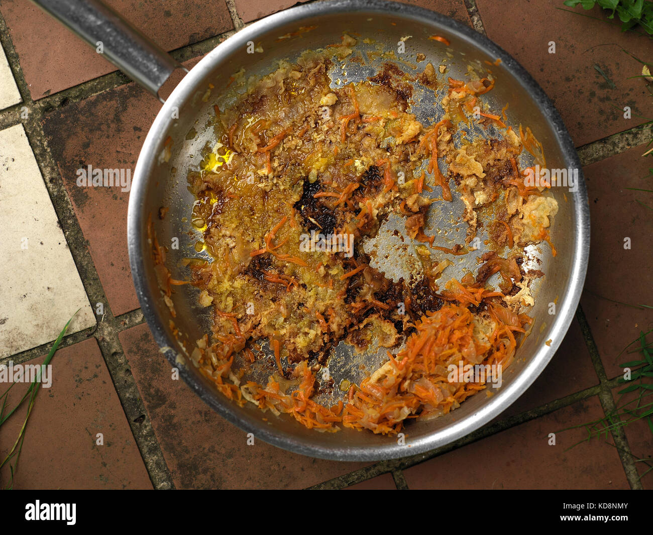 A frying pan needs to be washed placed on a tiled floor, overhead shot ...
