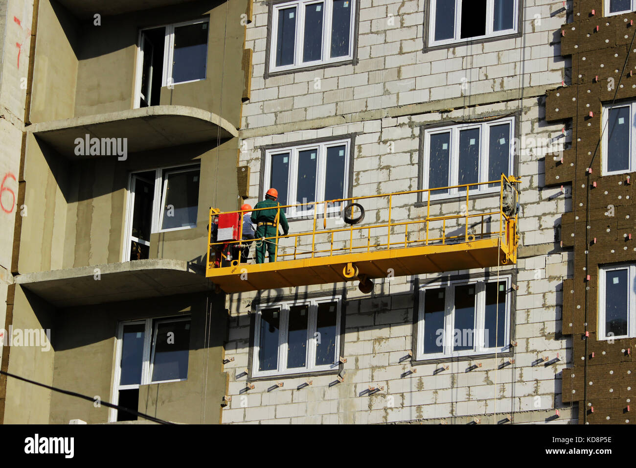 work with yellow front two suspended cradle with workers on a newly ...