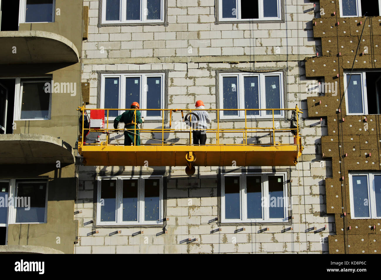 work with yellow front two suspended cradle with workers on a newly ...
