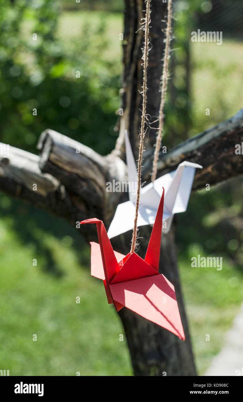 Origami cranes in the garden. Figures of paper in the nature. Red and ...