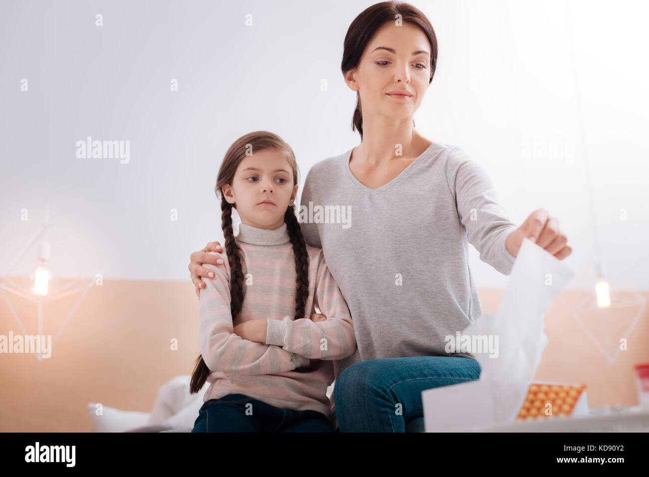 Serious child sitting with a smiling woman Stock Photo - Alamy