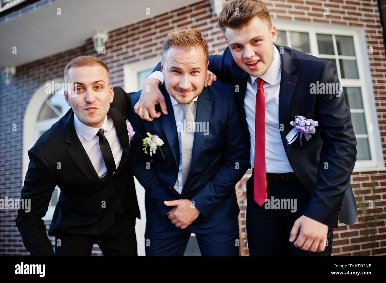 Handsome groom in his wedding tuxedo posing with groomsmen or best men ...