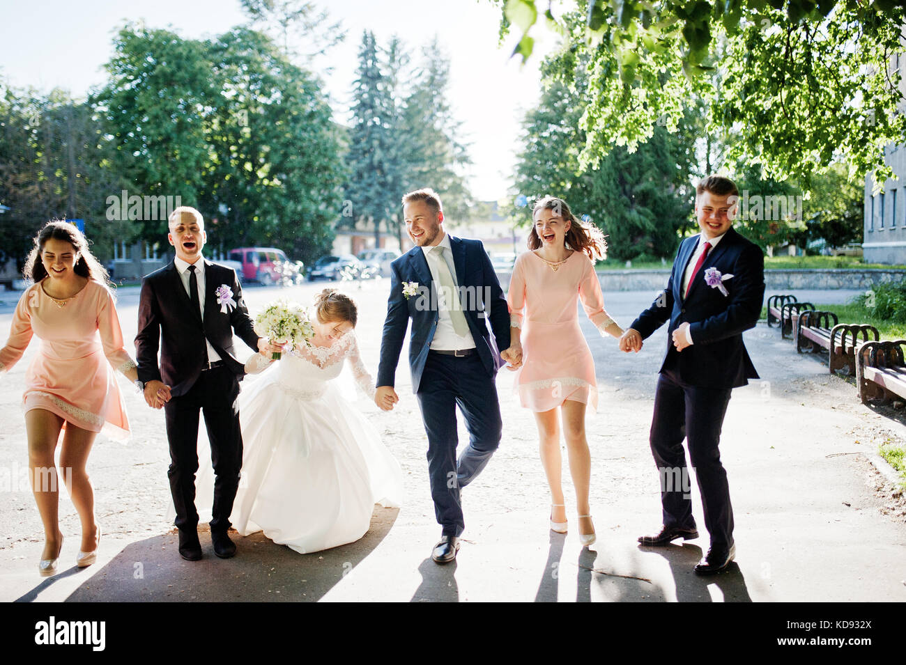 Happy wedding couple and bridesmids with groomsmen running and jumping ...