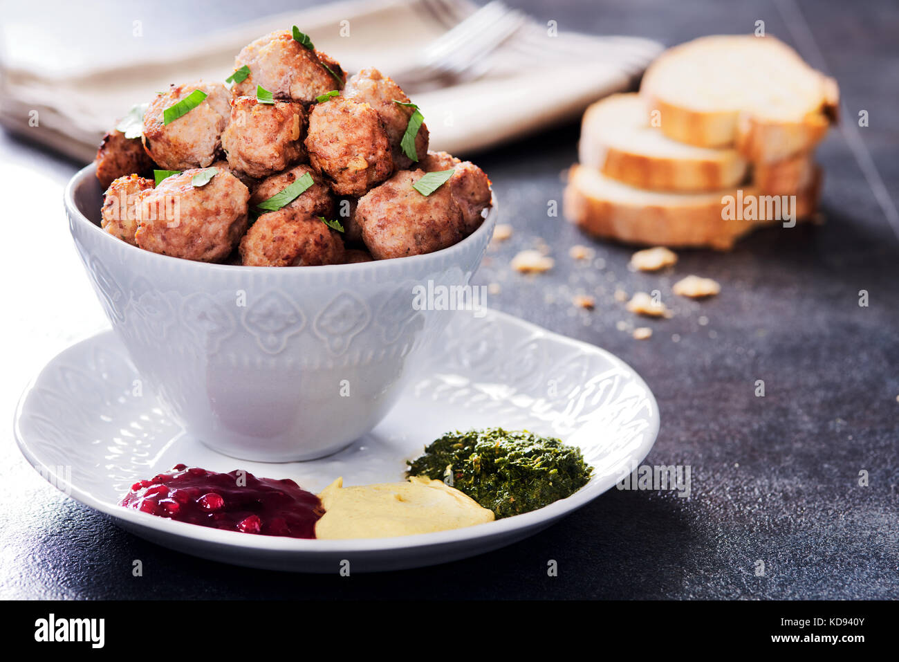 swedish meatballs in a bowl with several sauces on a plate, grey blue ...