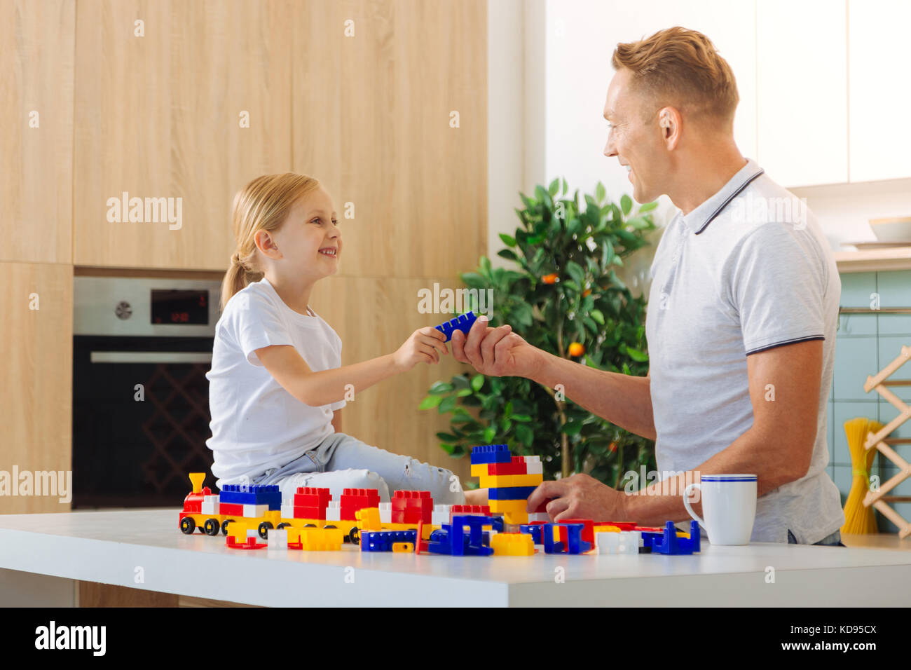 Happy cheerful girl taking a constructor set piece Stock Photo - Alamy