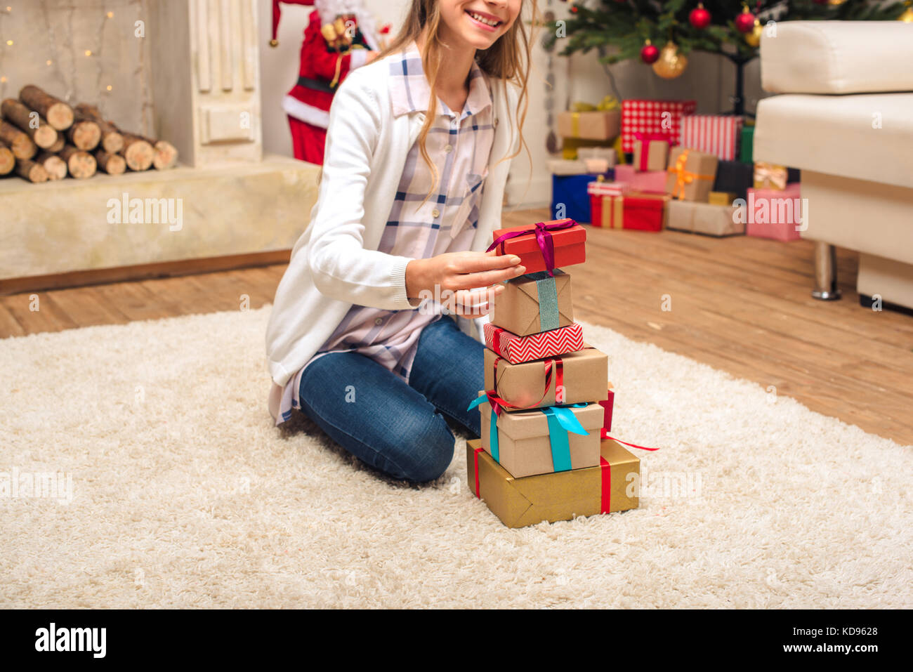 cropped shot of smiling girl stacking gift boxes on carpet at christmastime Stock Photo - Alamy