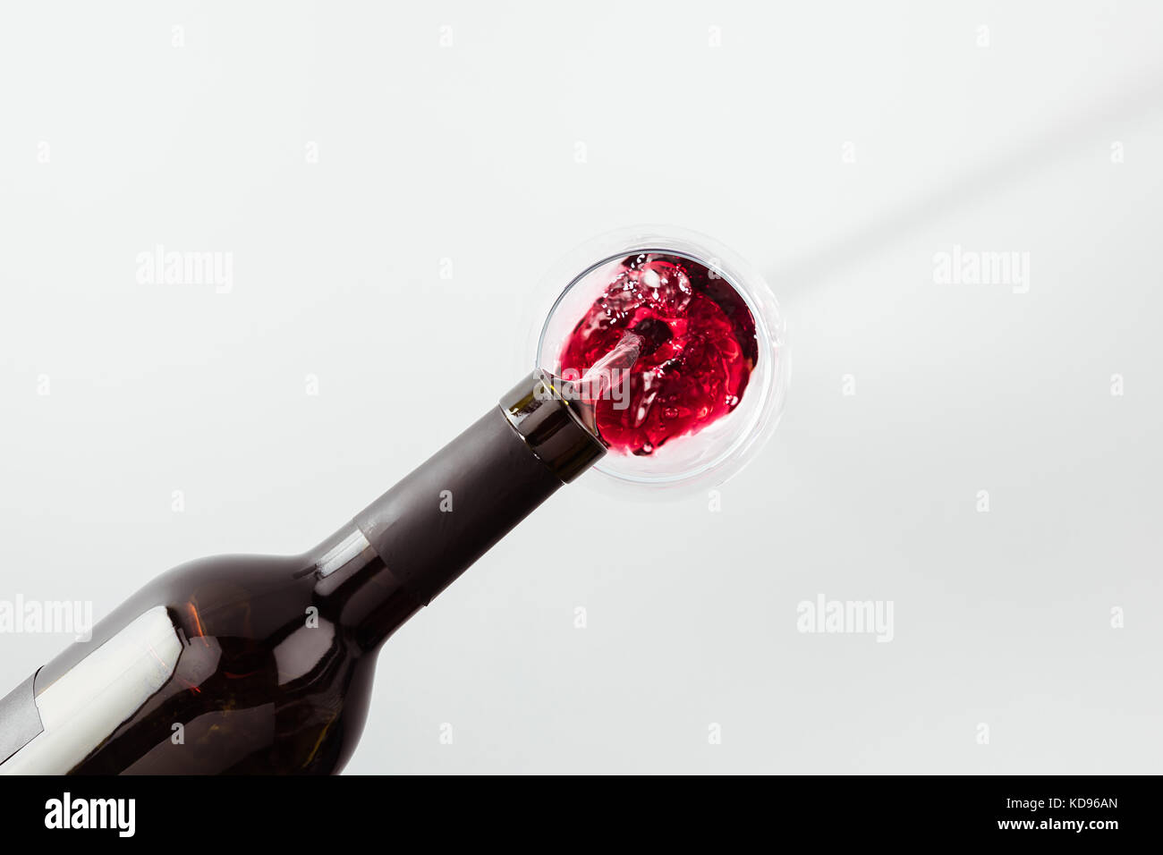 close-up view of red wine pouring from bottle in glass isolated on ...