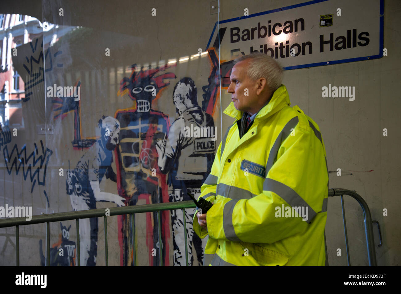 Security guard at the Barbican guarding Banksy graffiti of police ...