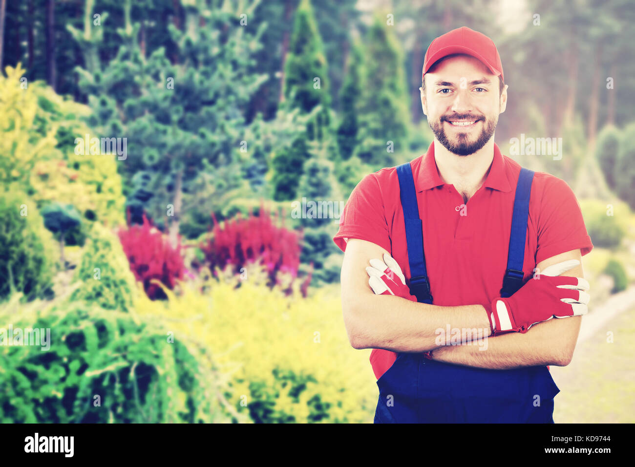 young smiling gardener with crossed arms standing in garden Stock Photo ...