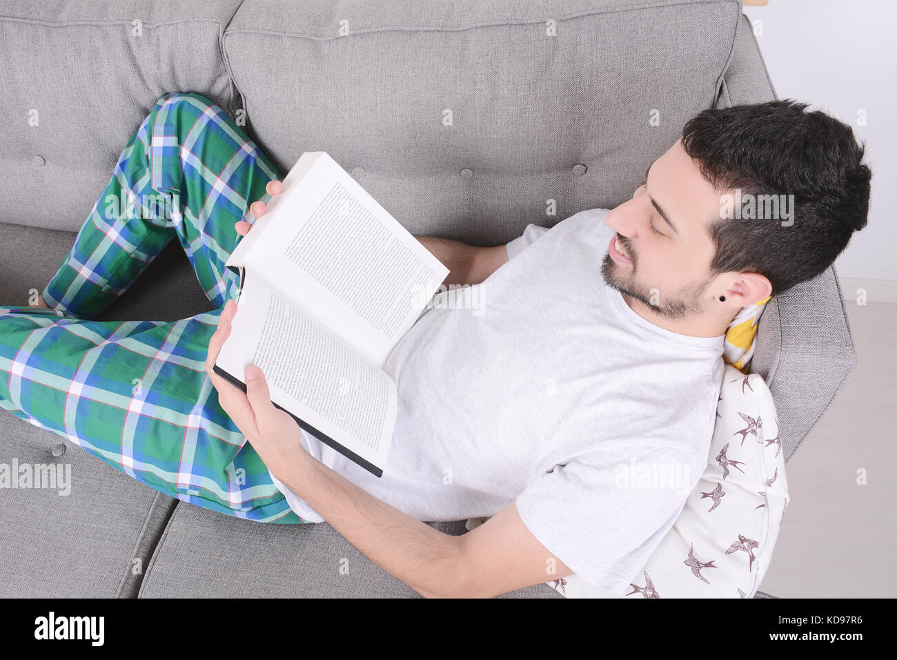 Attractive young man relaxed and reading a book. Indoors Stock Photo ...