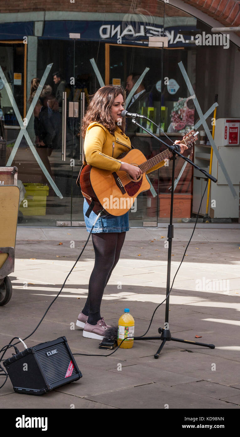 A young female busker singing and playing guitar in Stratford upon Avon ...