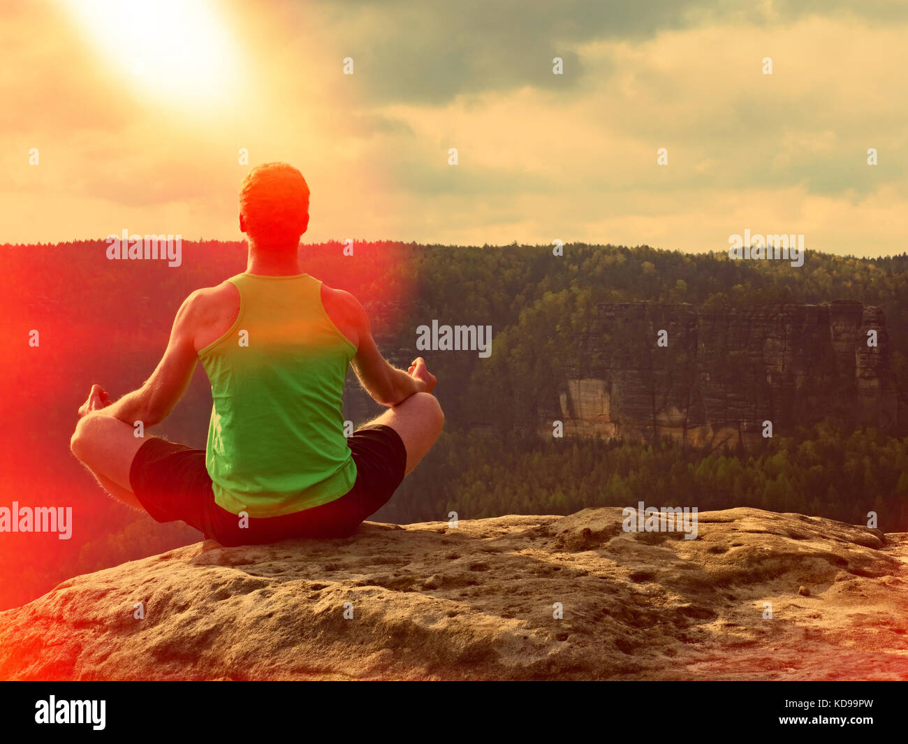 Lens defect. Man meditating in Lotus Pose on rocky cliff. Sportsman ...