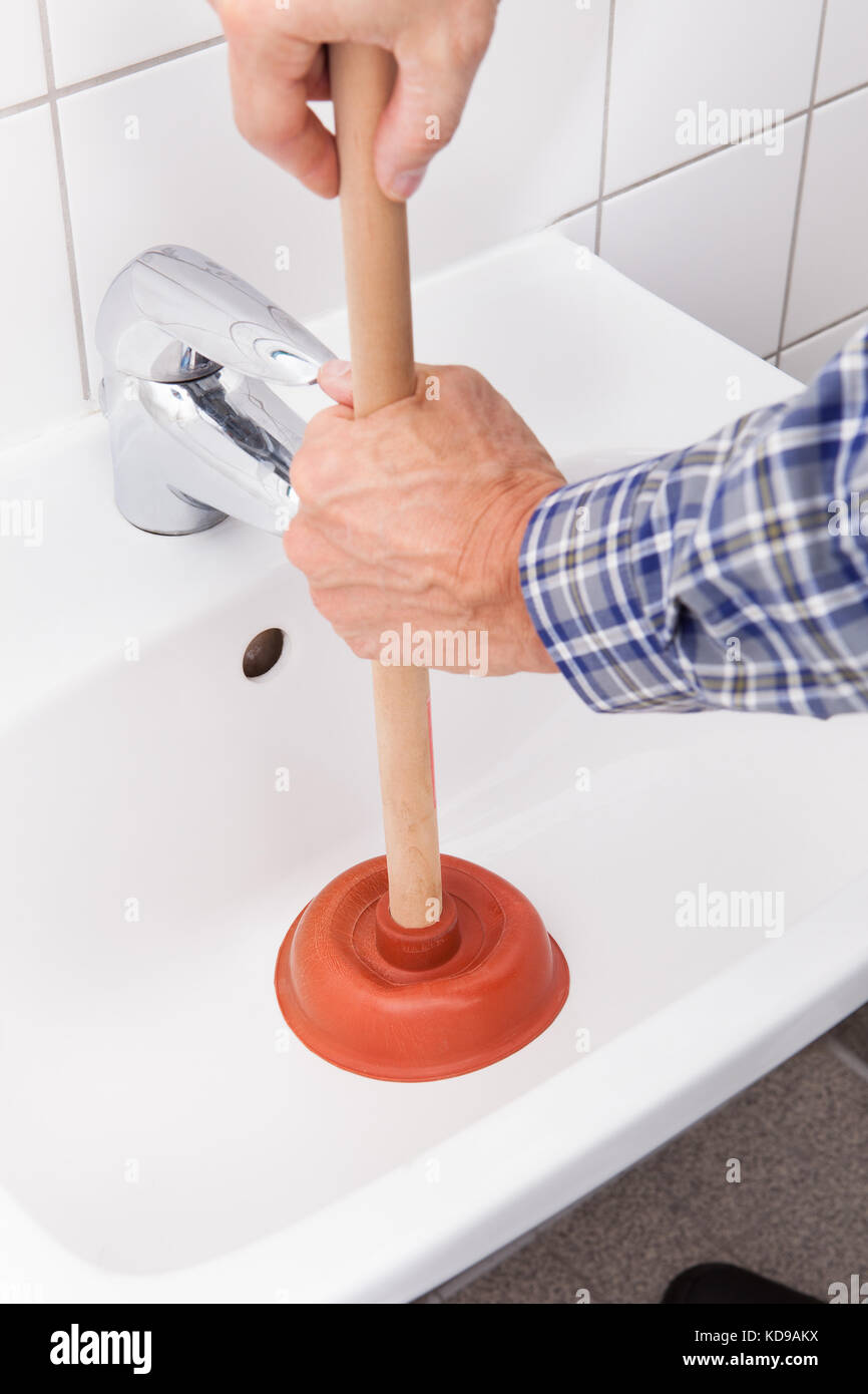 Portrait Of Male Plumber Using Plunger In Bathroom Sink Stock Photo - Alamy