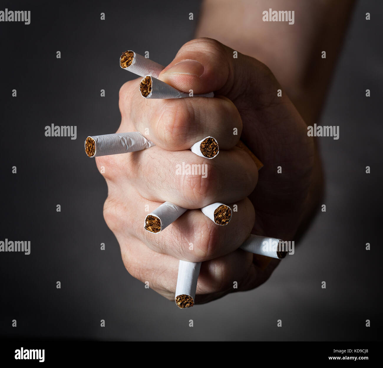 Male Fist Piercing Cigarettes Over Black Background Stock Photo - Alamy