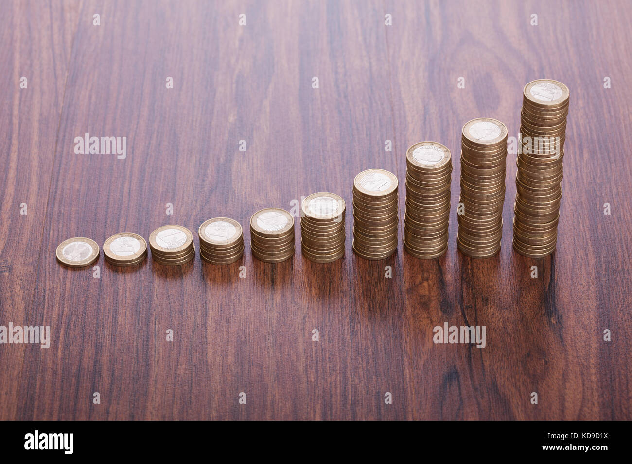 Stack Of Coins In A Row On Wooden Table Stock Photo - Alamy