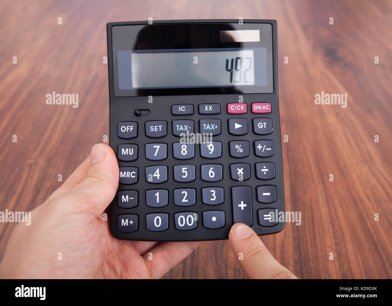 Close-up Of Person's Hand On Wooden Table Doing Calculation Stock Photo ...