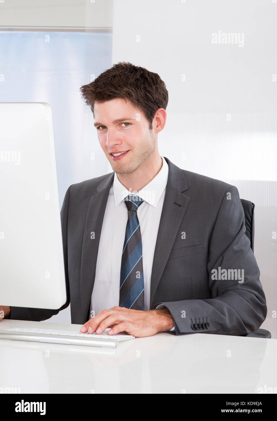 Portrait Of Young Businessman Using Computer At Desk Stock Photo - Alamy