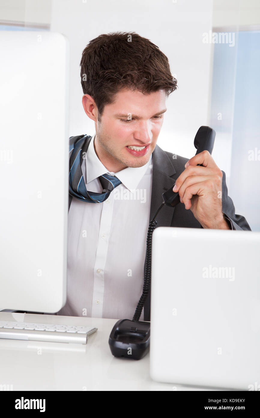Young Businessman Sitting In Front Of Computer Talking On Telephone ...