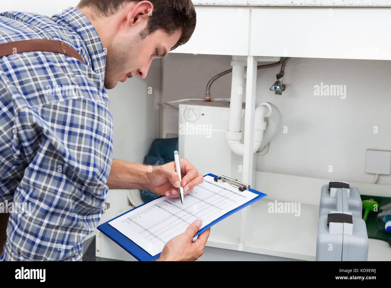 Handsome Young Plumber Writing On Clipboard With Pen In Kitchen Room ...