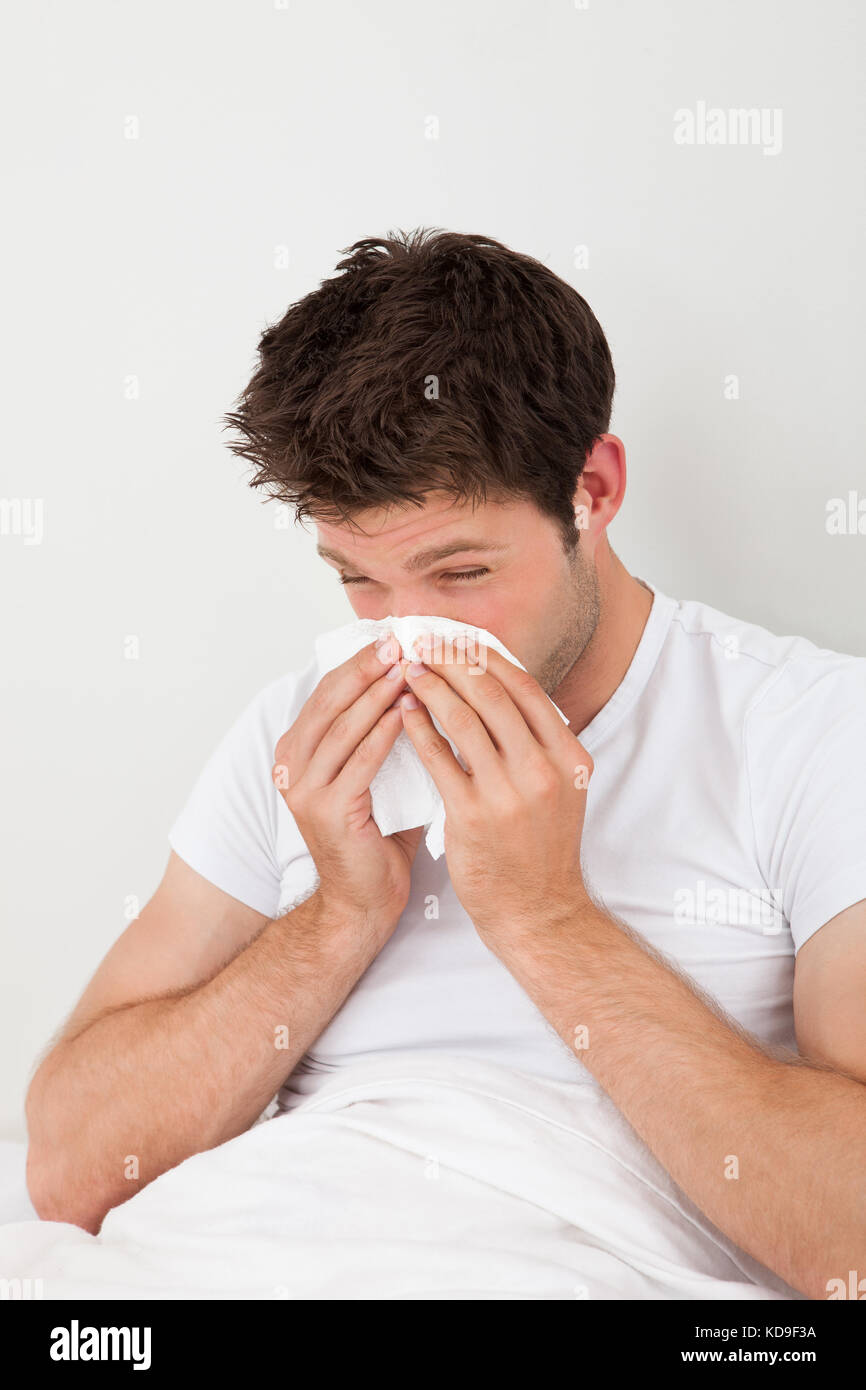 Young Man Blowing His Nose In A White Tissue Paper Stock Photo - Alamy