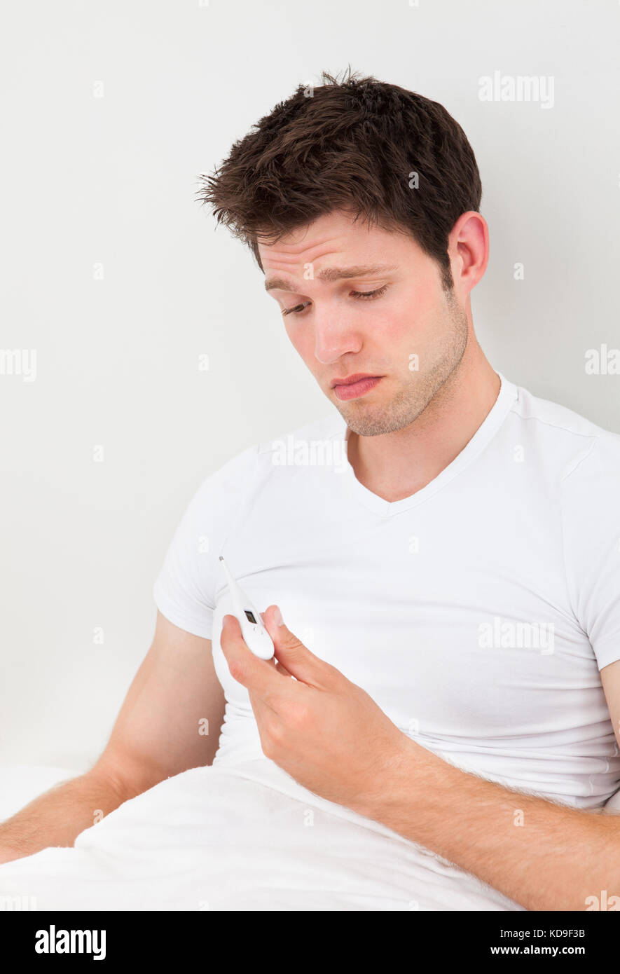 Young Man Checking His Temperature On A Digital Thermometer Stock Photo ...