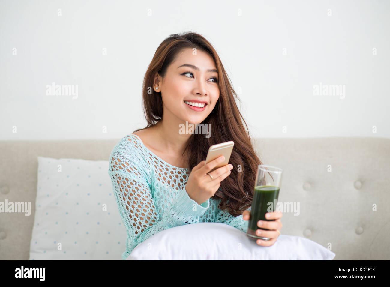 Smiling Young Asian Woman Drinking Green Fresh Vegetable Juice Or
