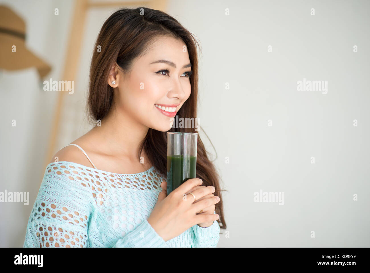 Smiling Young Asian Woman Drinking Green Fresh Vegetable Juice Or