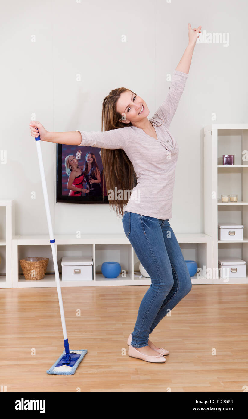 Portrait Of Young Woman Dancing In Home While Cleaning Floor Stock ...