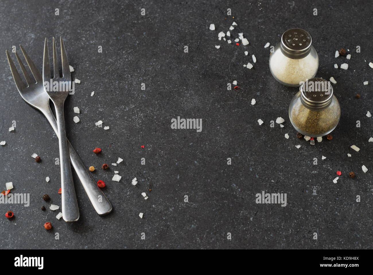 Grey abstract background with forks, salt and pepper shakers. Place for ...