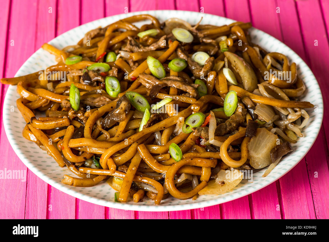 Oriental Shanghai Fried Beef Udon Noodles With Pak Choi Against a Pink ...