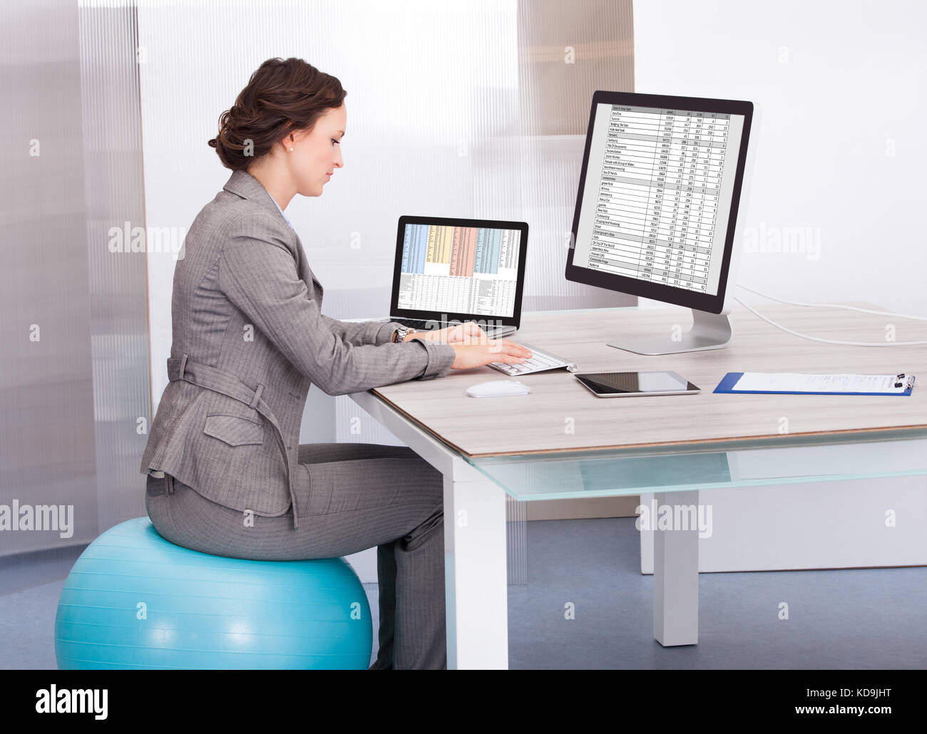 Young Businesswoman Sitting On Fitness Ball Using Computer In Office ...