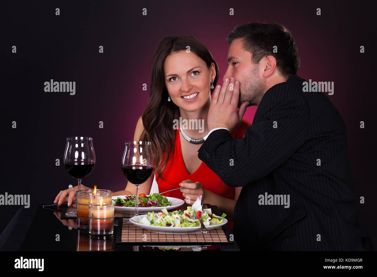 Man At Dining Table Whispering In Woman's Ear Stock Photo - Alamy