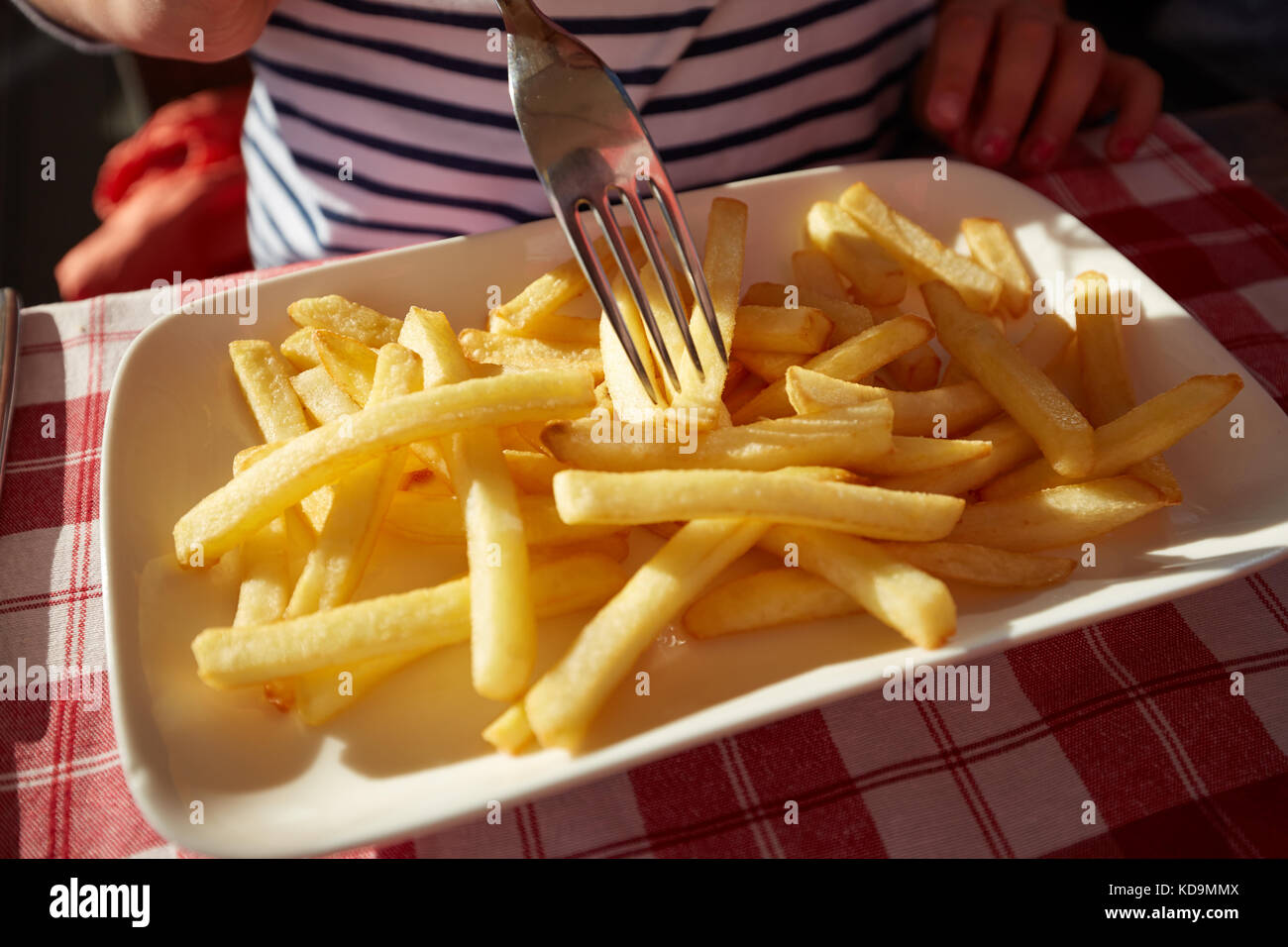 Close up photo preschool girl eats french fries potatoes sitting in ...