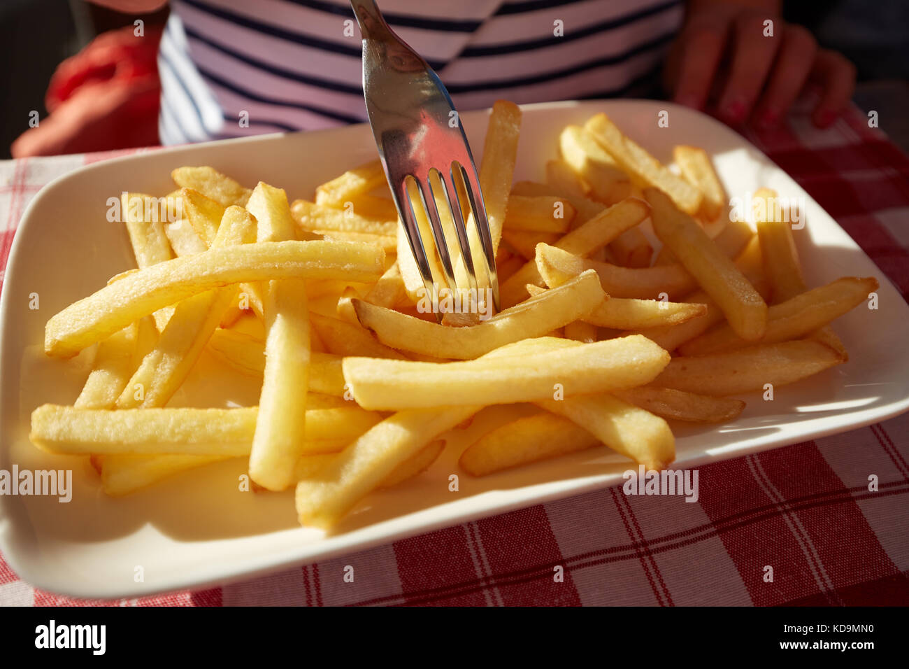 Close up photo preschool girl eats french fries potatoes sitting in ...
