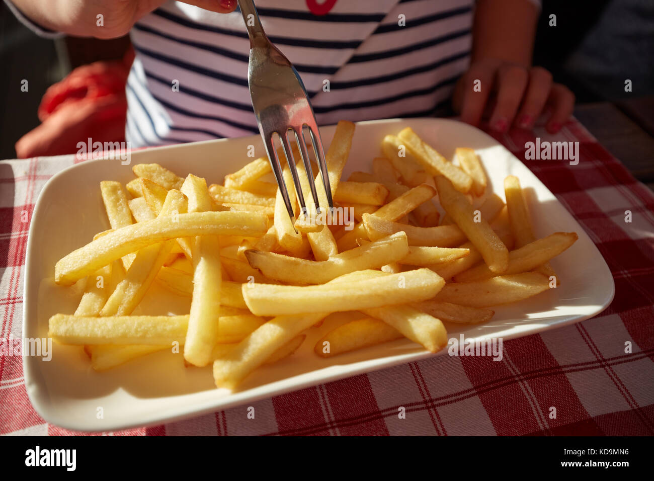 Close up photo preschool girl eats french fries potatoes sitting in ...