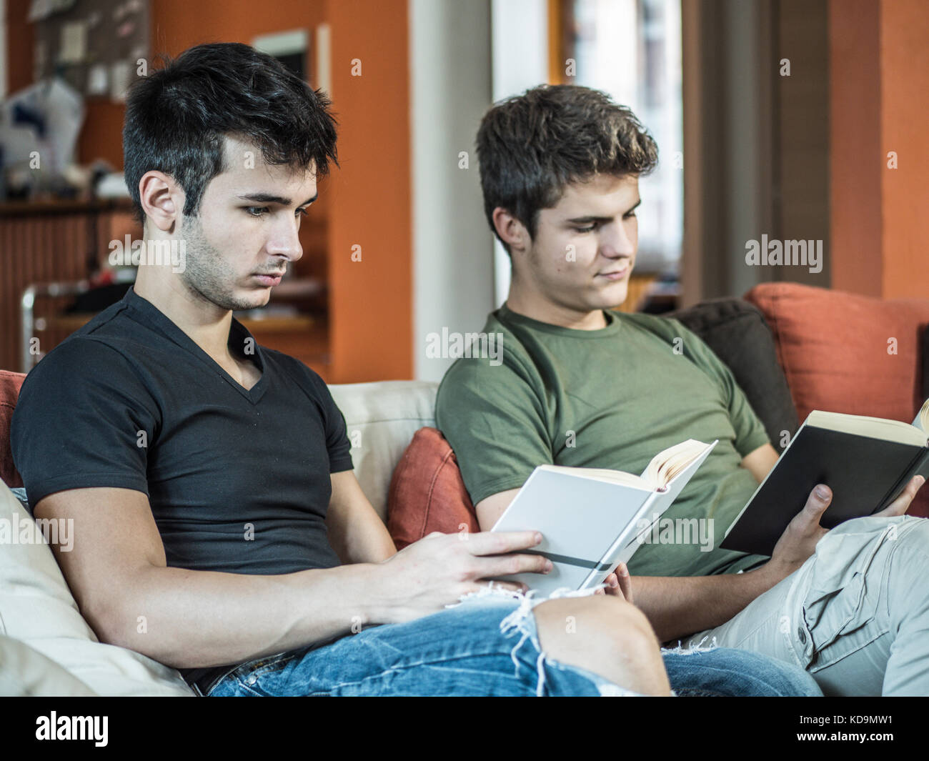 Men reading textbooks on sofa Stock Photo - Alamy